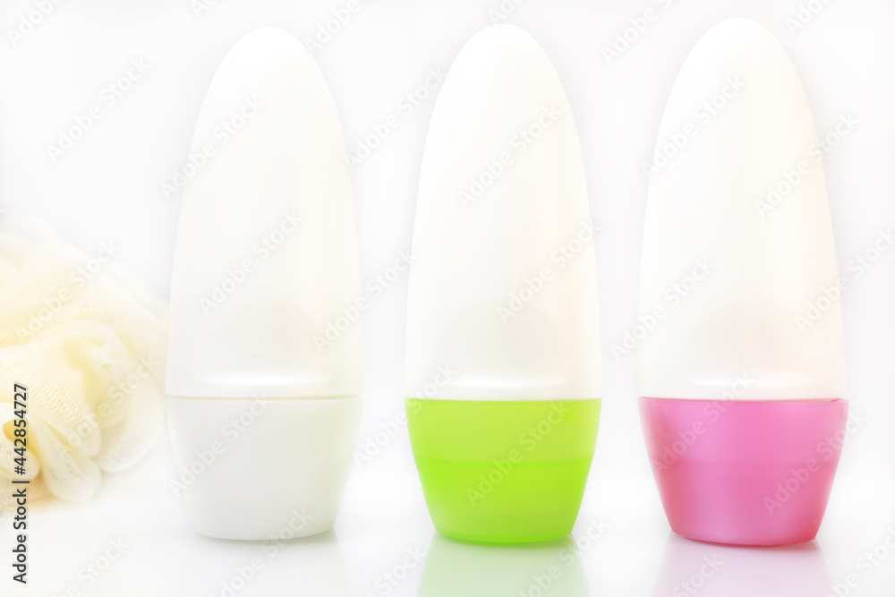 Three types of roll-on antiperspirant and shower sponge on white ...