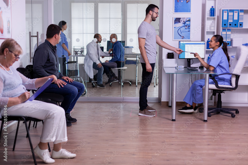 Crowded hospital waiting area with people filling form for medical ...