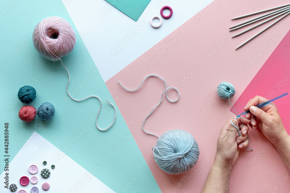 Wool yarn, cotton balls and knitting needles. Hands with crochet ...