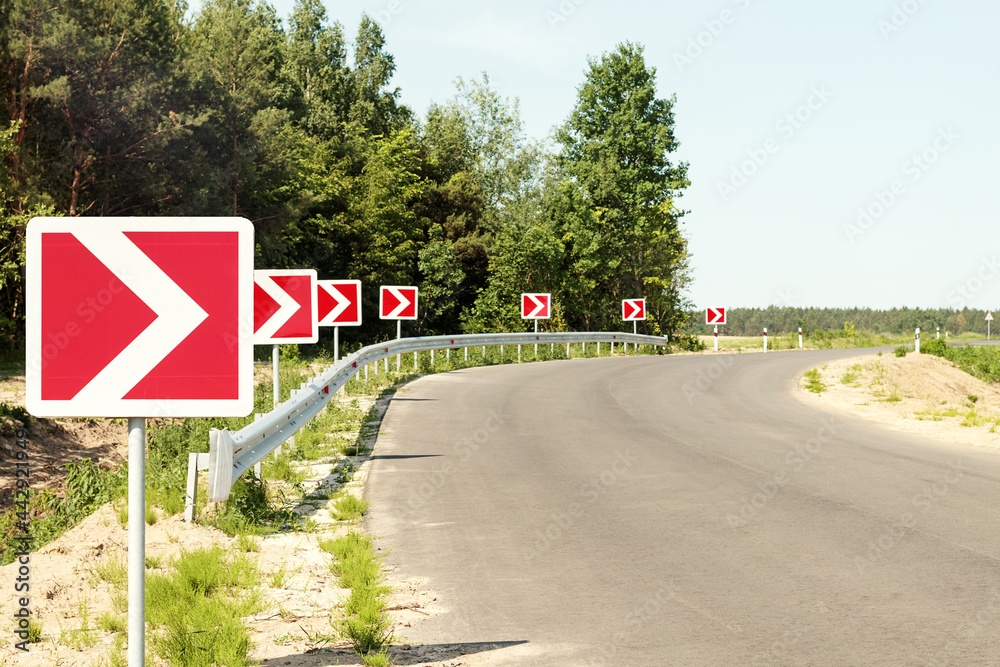 Red and white traffic signs warning about dangerous sharp turn of road ...