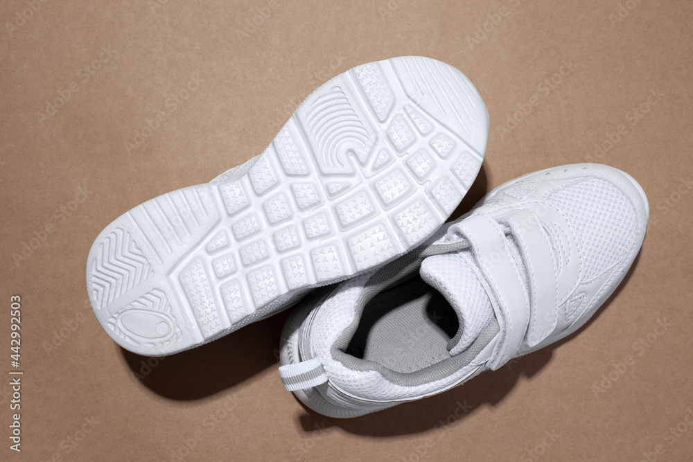 macro top view Two white woman sneakers, one sneaker lies sole up with ...