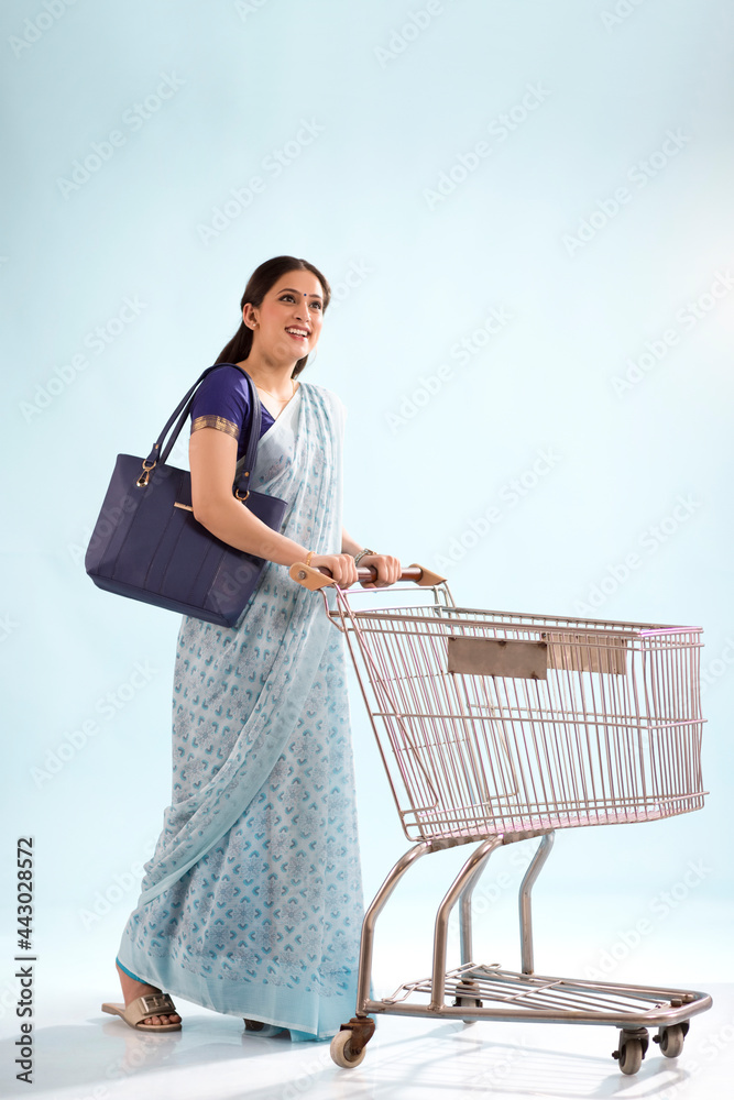 A young woman walking with a trolley. Stock Photo | Adobe Stock