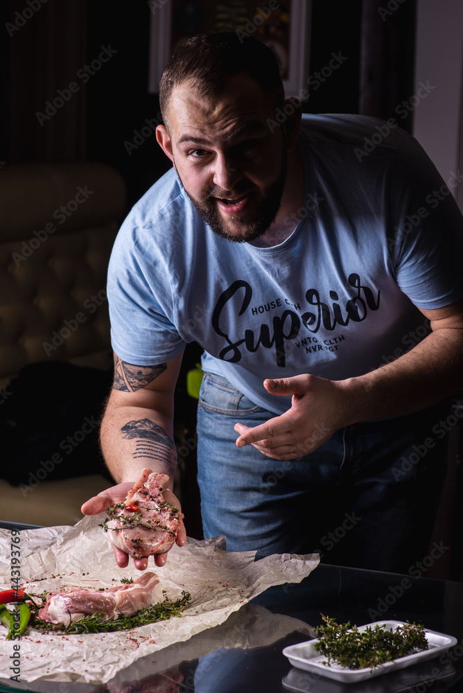 a young man with a beard holds raw meat in his hands, in front of his ...