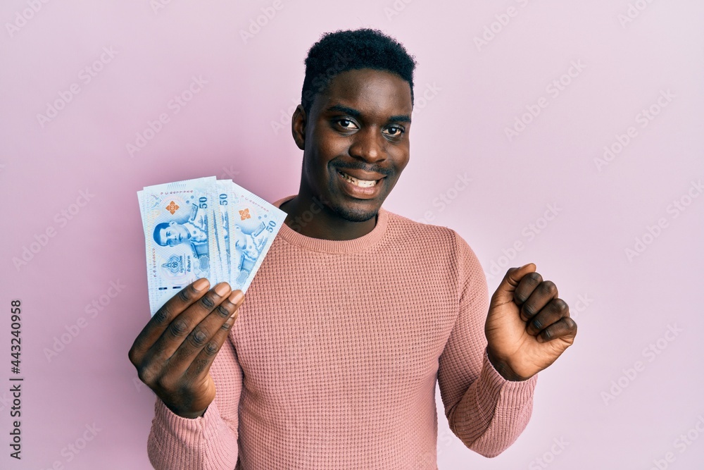 Handsome black man holding 50 thai baht banknotes screaming proud ...
