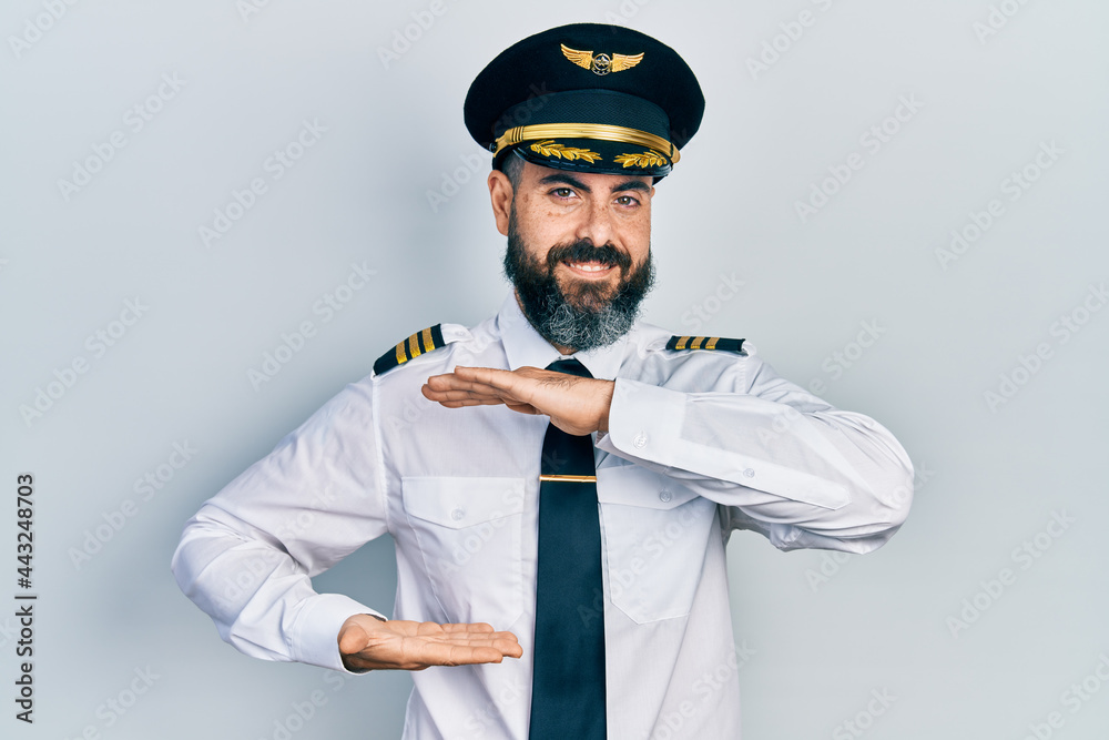 Young hispanic man wearing airplane pilot uniform gesturing with hands ...