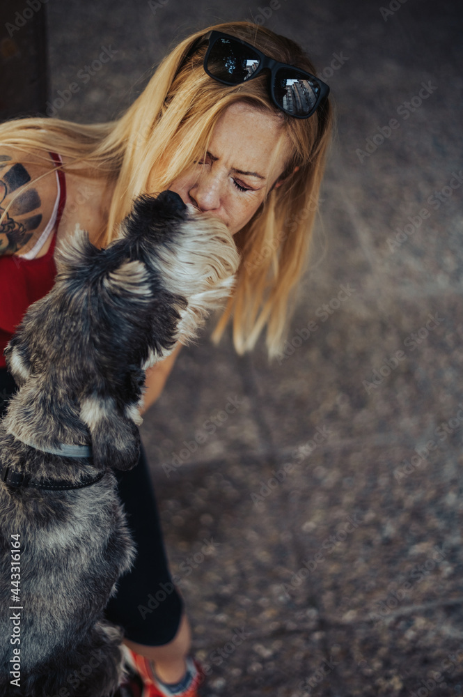 Woman kissing her dog in the mouth while having a good time outside ...