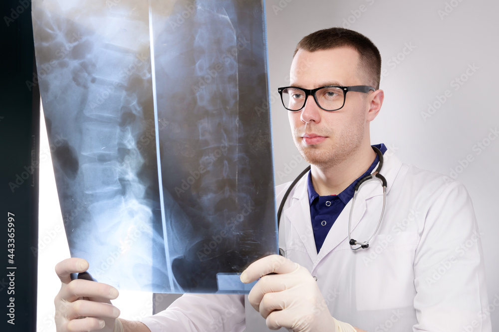 Young doctor radiologist in glasses and medical clothes looks at the ...