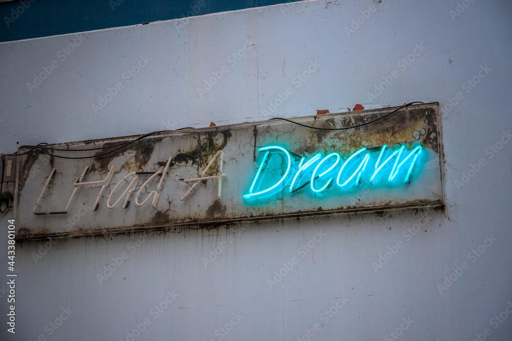 Blue neon sign I Had A Dream with only Dream being lit on London urban ...