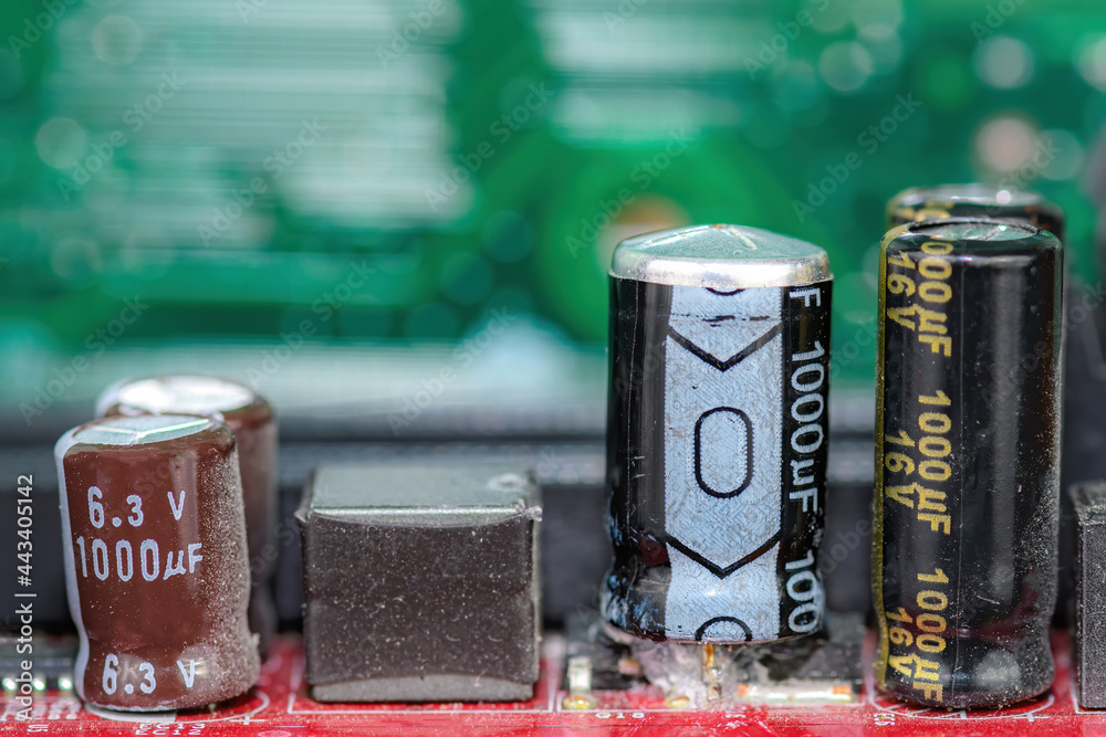 Damaged capacitor on a circuit board. Top is bulged out showing failure ...