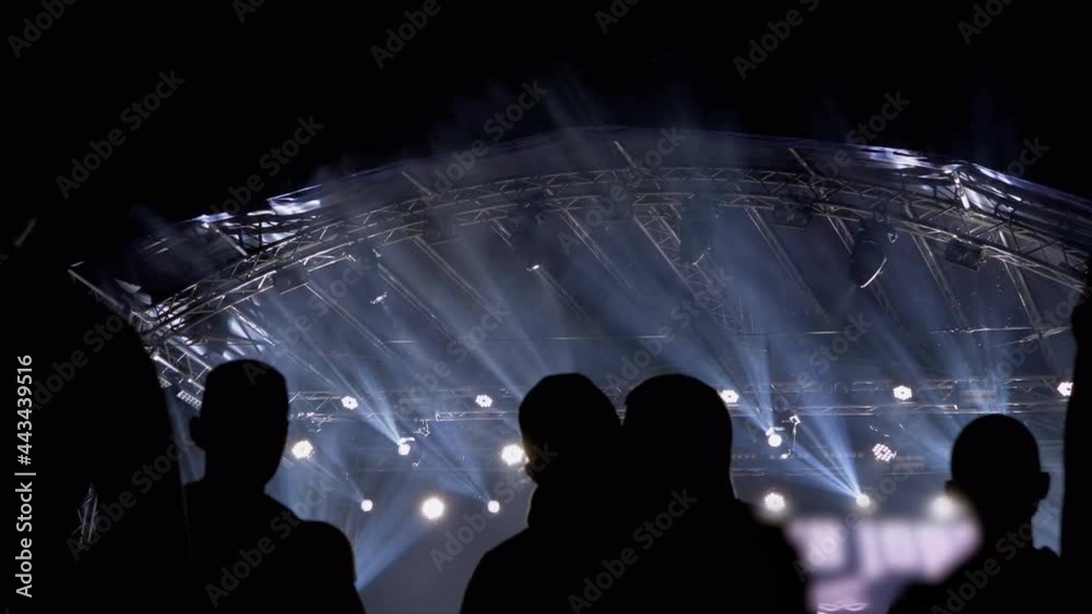 Silhouettes of two hugging people at night at a concert. Stage lighting ...