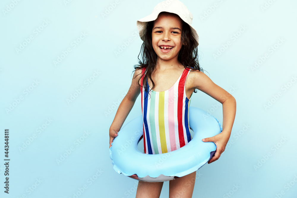 The positive little girl stands in an inflatable swim ring wears ...