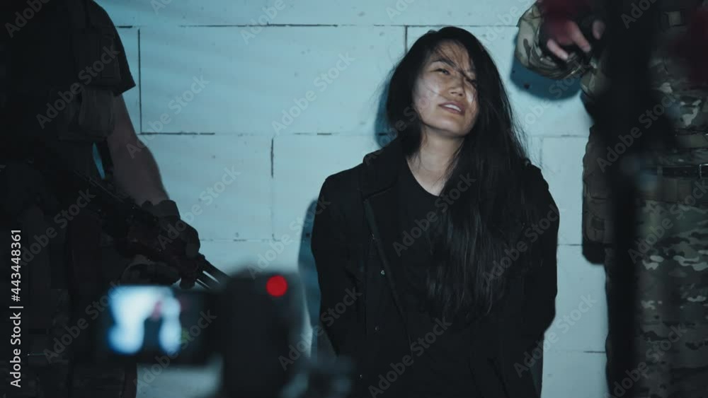 Handheld slowmo shot of female Asian woman held hostage by terrorists ...