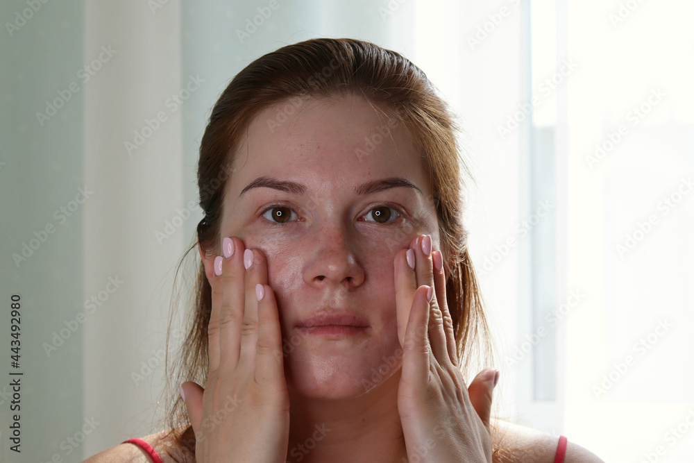 Dissatisfied woman touching face skin front bathroom mirror. Young ...