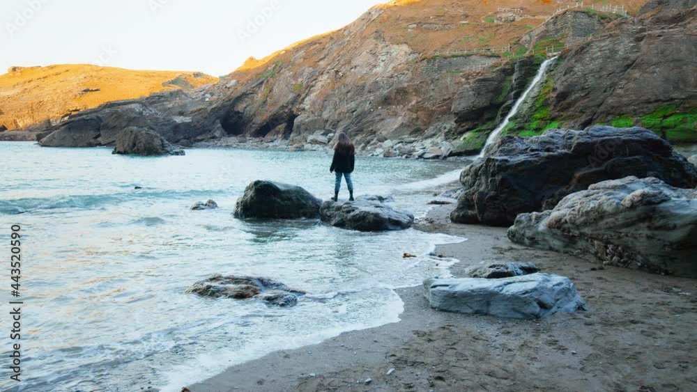 A girl exploring a dark terrifying cave in Tintagel Castle, Cornwall ...