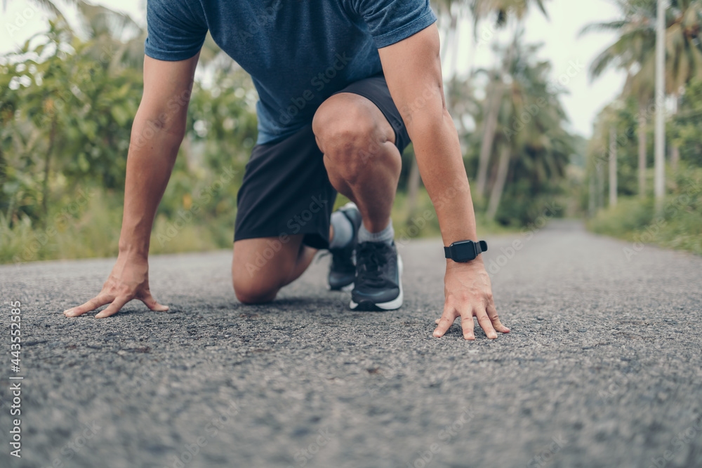 Athlete man in running start pose on the road in the forest. Start and ...
