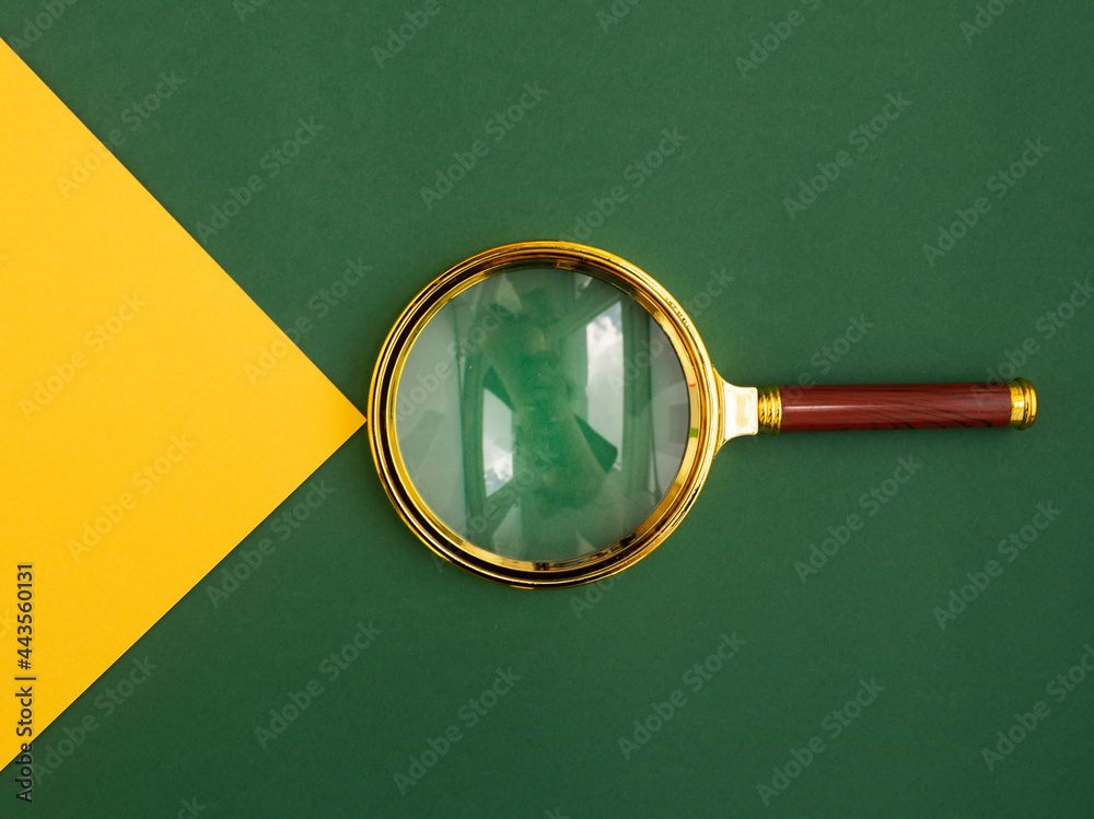 Magnifying glass over green background with yellow paper beam as symbol ...