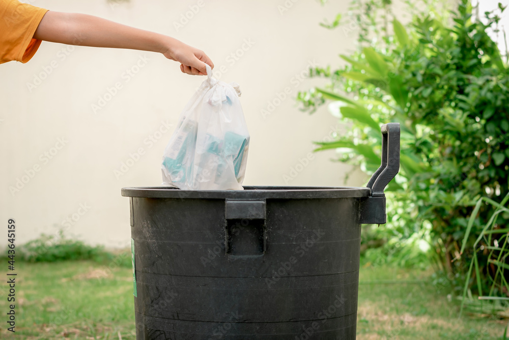 Hand of human throwing trash in plastic bags into the trash in the ...