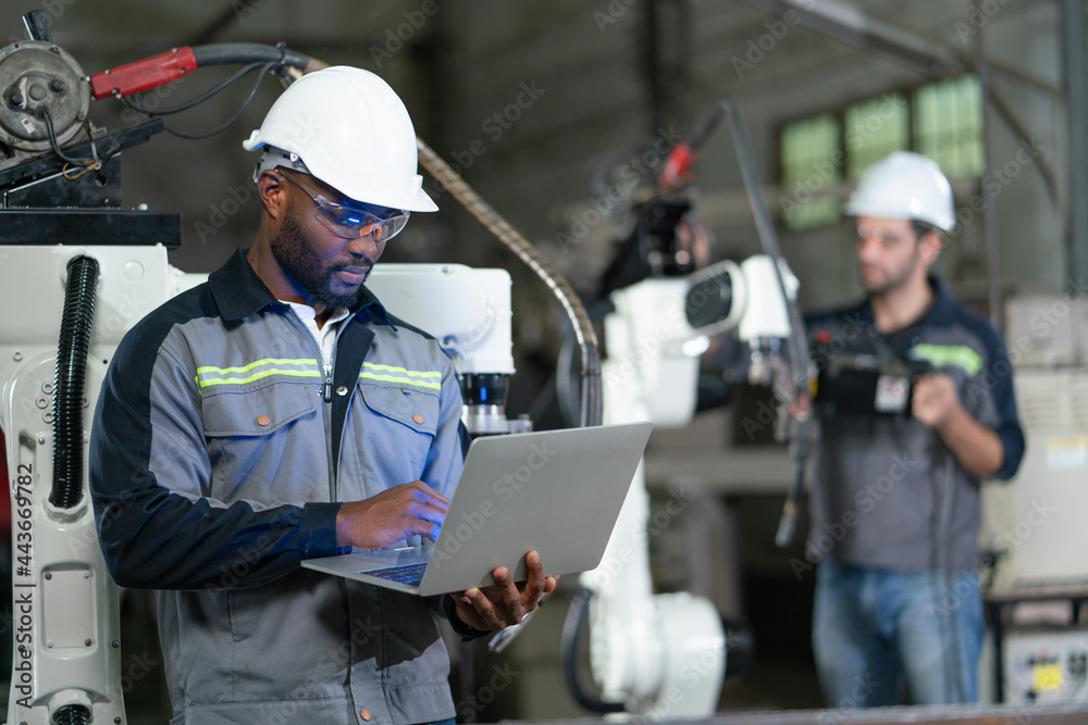 Male automation engineer checking and inspection control a robot arm ...