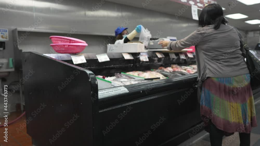 This video shows an elder asian woman taking her fish order from the ...