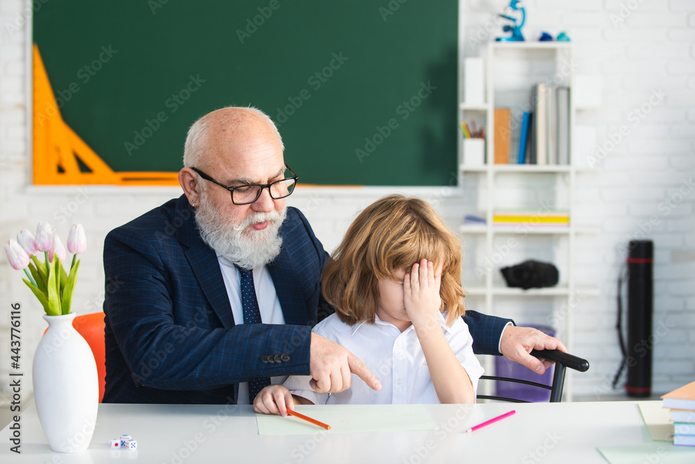 Sad school boy grandson with problem reading book and writing with old ...