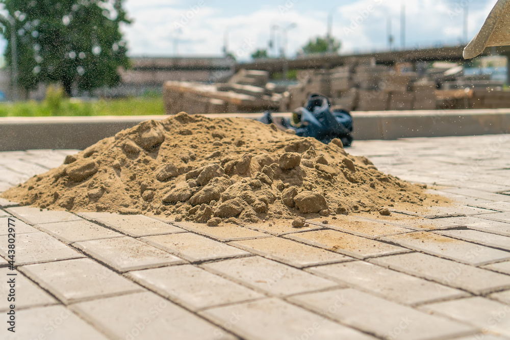 Close-up of a pile of sand lying on the new sidewalk to seal the seams ...