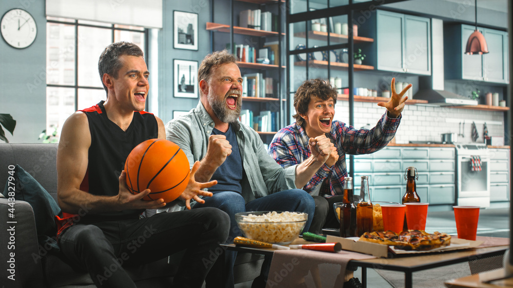 At Home Three Happy Basketball Fans Sitting on a Couch Watch Game on TV ...