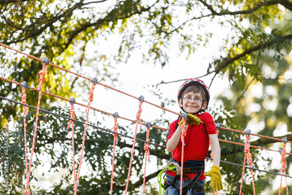 Boy In Adventure Park having fun in high wire park. Child climbs in a ...