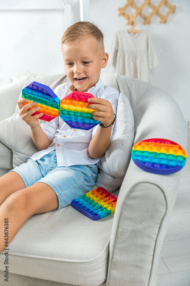 Portrait blonde boy with pop it sensory toy different forms. Boy ...
