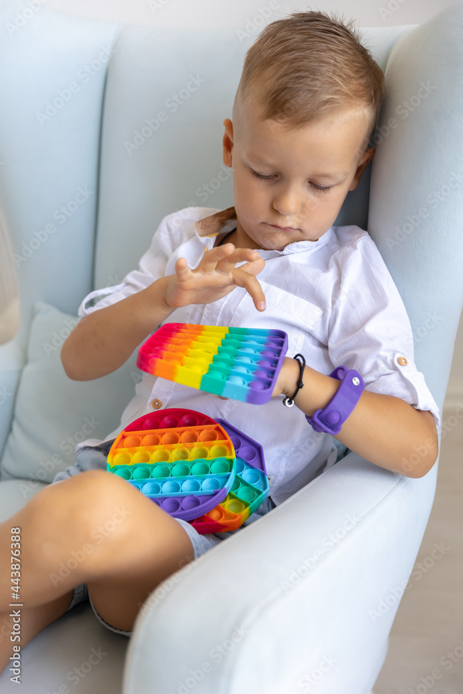 Portrait blonde boy with pop it sensory toy different forms. Boy ...