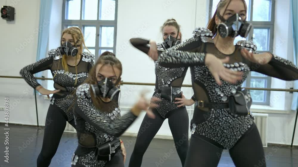 Group of slim women dancing in black mirror costumes with respirators ...