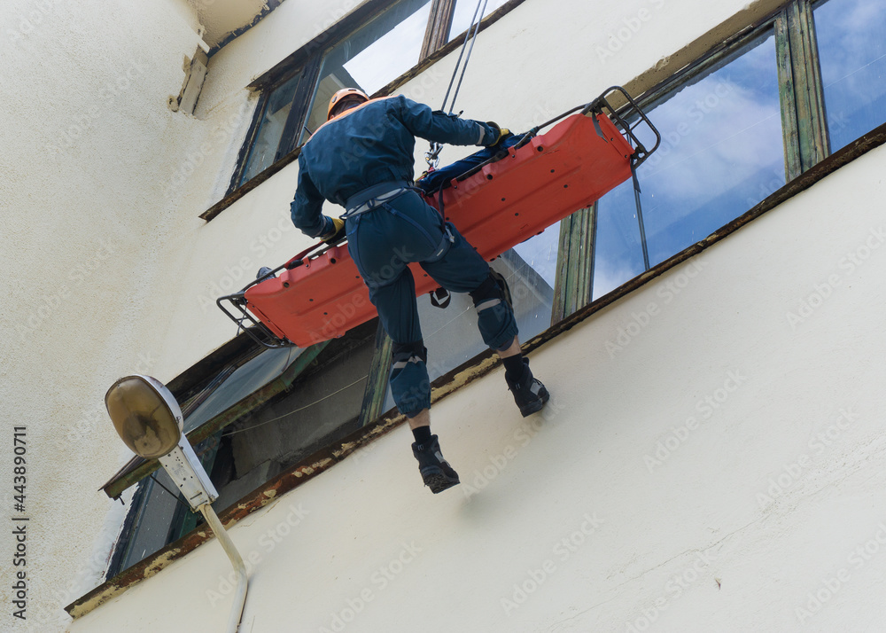 Rescue operation. The rescuer lowers the body in a stretcher from a ...
