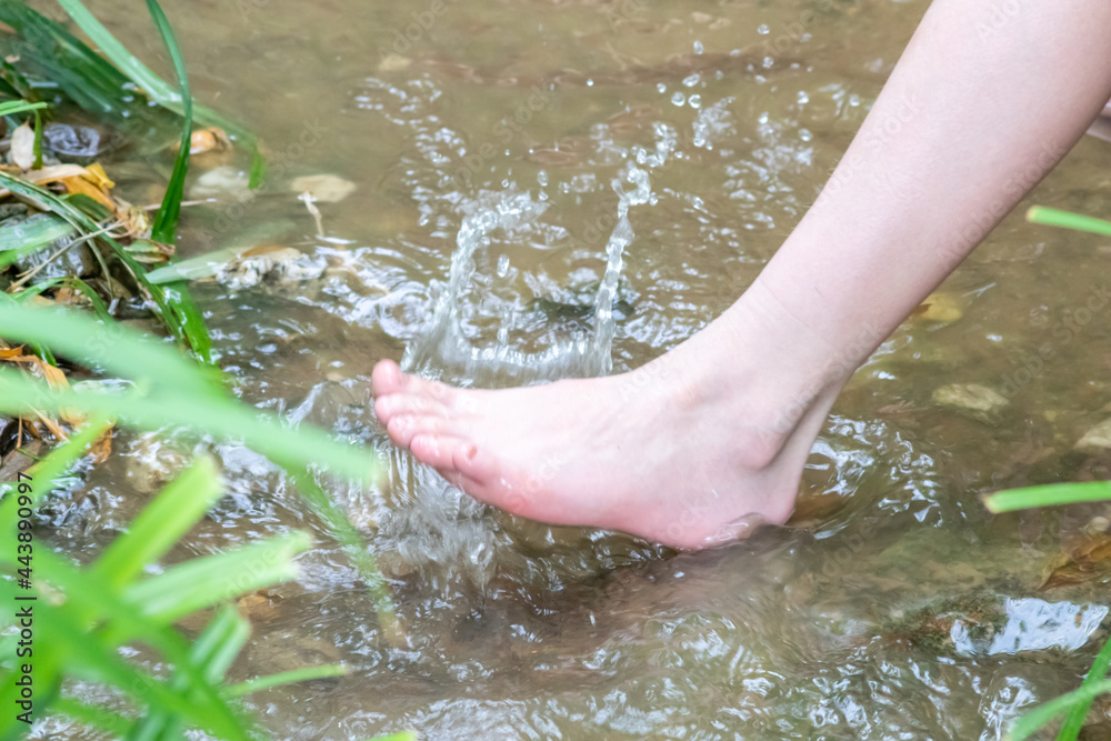 Young boy playing barefoot with clear water at a little creek using his ...