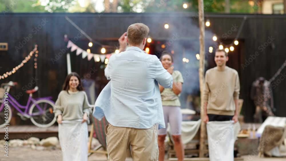Diverse friends having fun at party competing in sack race in slow ...