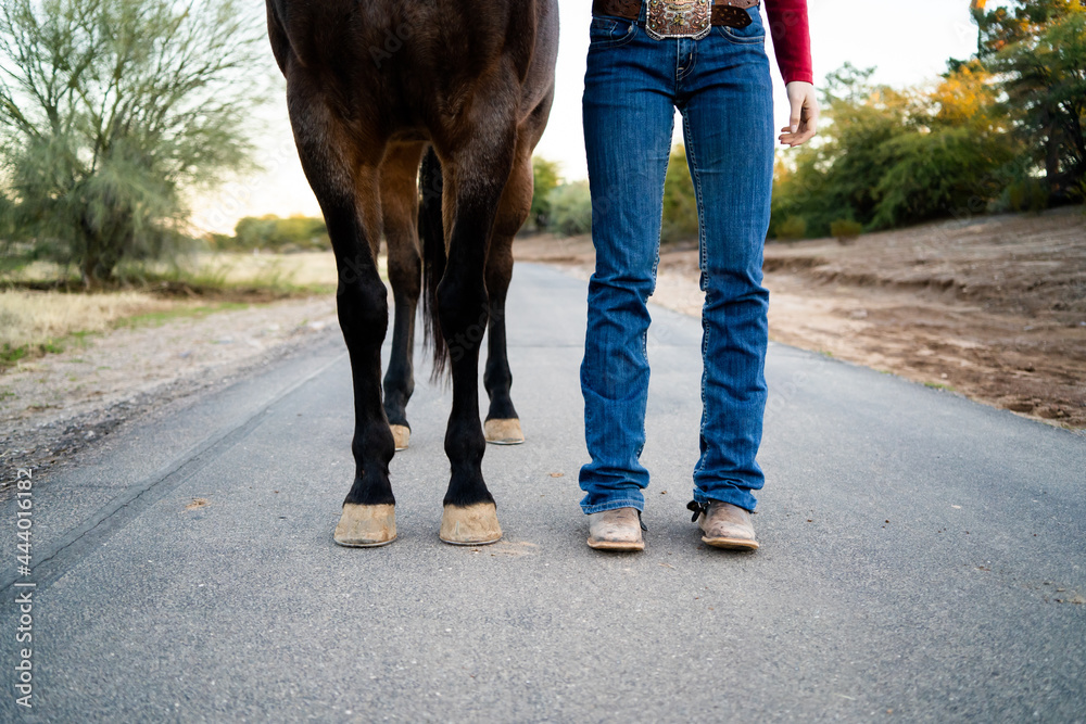 perspective of horse hooves and a woman's feet with cowboy boots ...