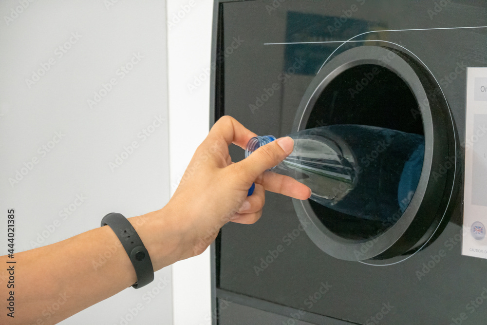 Reverse vending machine. Woman hand put empty plastic bottle in the ... Reverse vending machine. Woman hand put empty plastic bottle in the ...