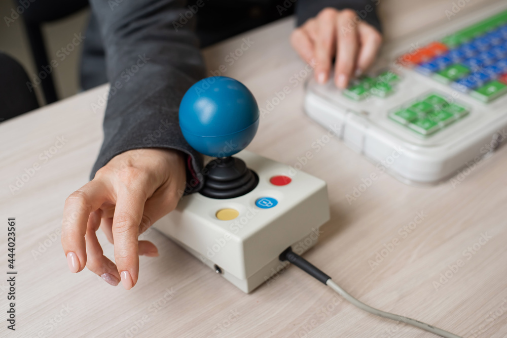 An unrecognizable woman with cerebral palsy is typing on the keyboard ...