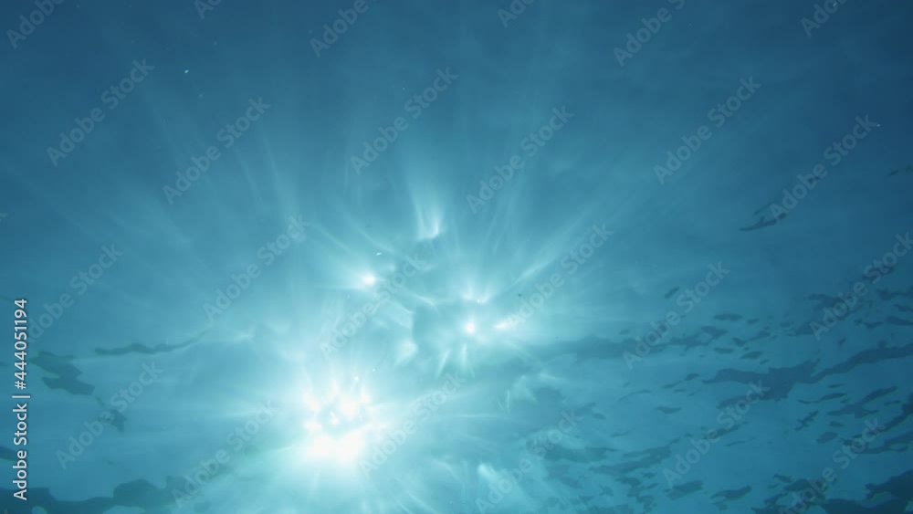 Sun beams penetrating wavy ocean surface. Ocean background light shafts ...