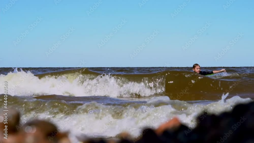 close up view of beating waves at the beach. Boys are running in water ...