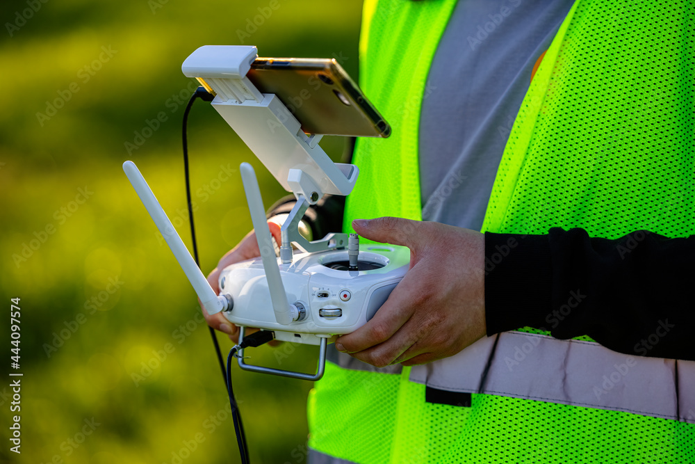 An unmanned aerial vehicle pilot in a reflective vest controls the ...