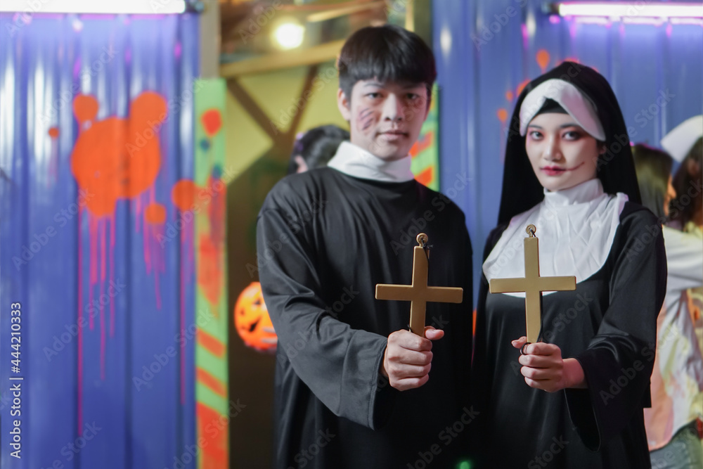Selective focus on the cross in hands of Asian young couple dressed as ...