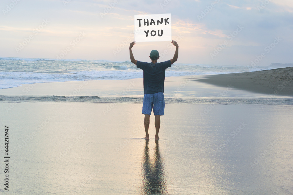 Thank you. Man standing alone with arm raised holding thank you sign on ...
