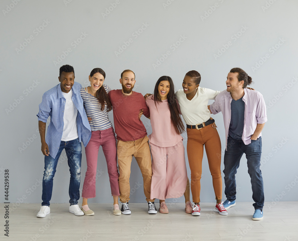 Studio group portrait of cheerful diverse millennial friends standing together. Happy young ...