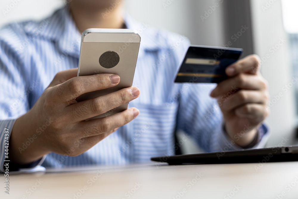 A woman holding a cell phone and credit card, she fills in her credit ...