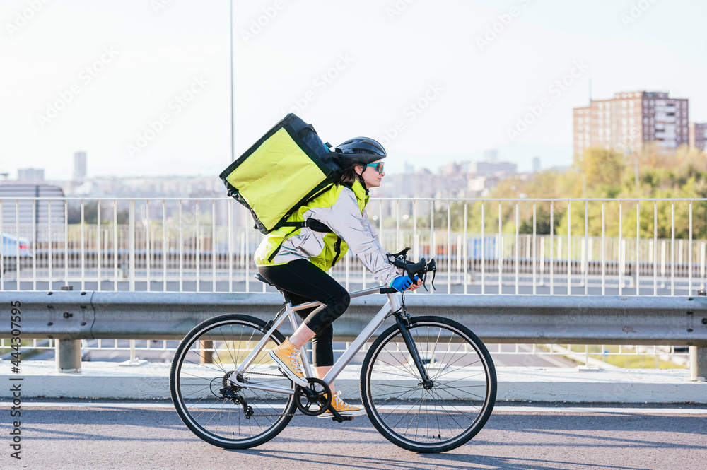 Delivery woman riding bicycle on bridge Stock Photo | Adobe Stock