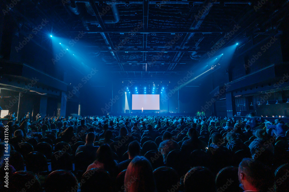 Audience sitting in front of stage with screen Stock Photo | Adobe Stock