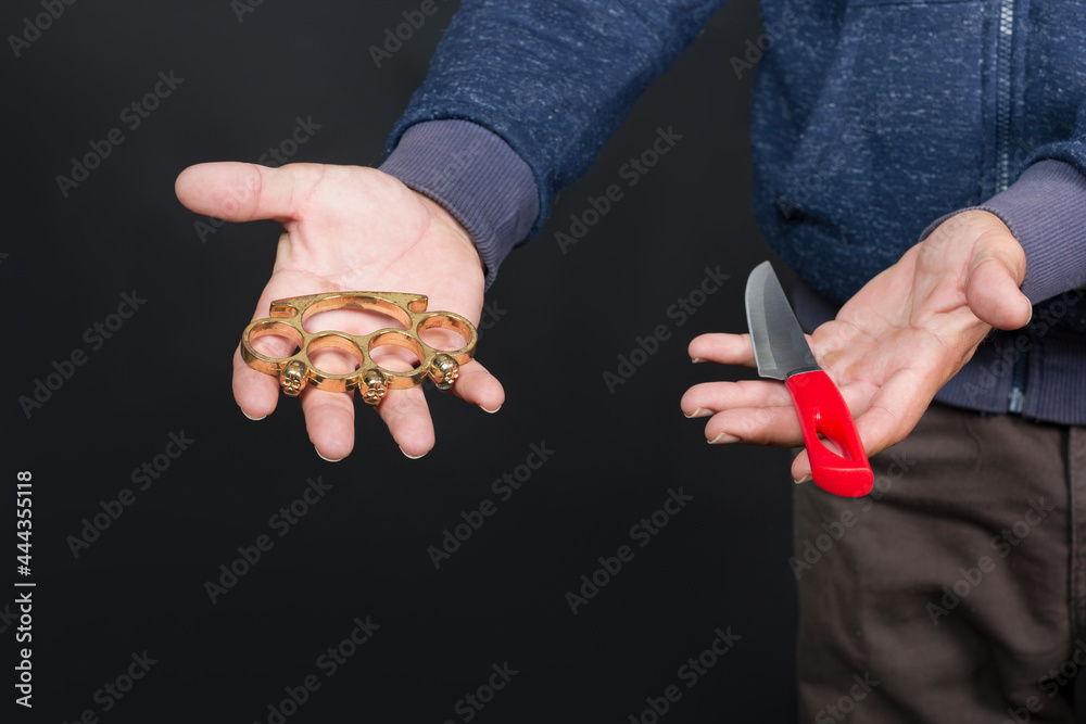 Brass knuckles and knife on the man`s palm. Metal brass knuckles in the ...