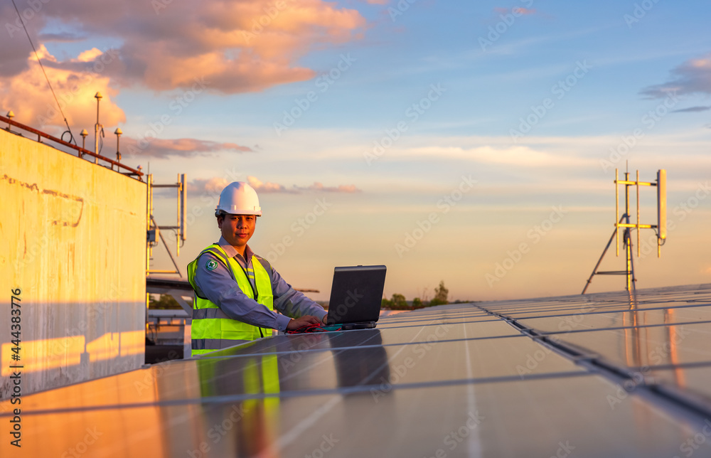 Foto de Engineer using laptop at solar panels on rooftop at sunset sky ...
