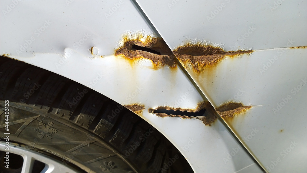 Sheet metal corrosion above tyre wheel of old white car body. Rusty ...