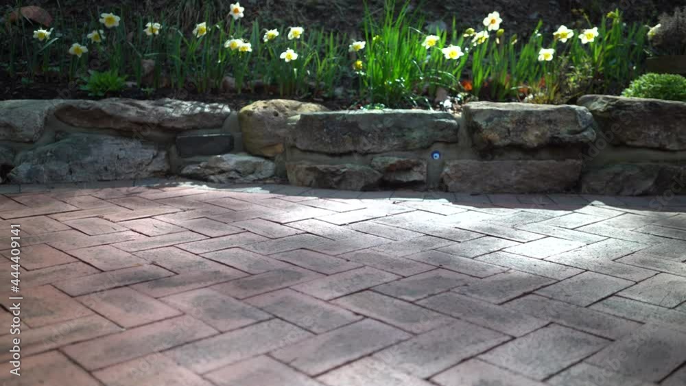 Slider to the left with brick herringbone pavers in focus, rock wall ...