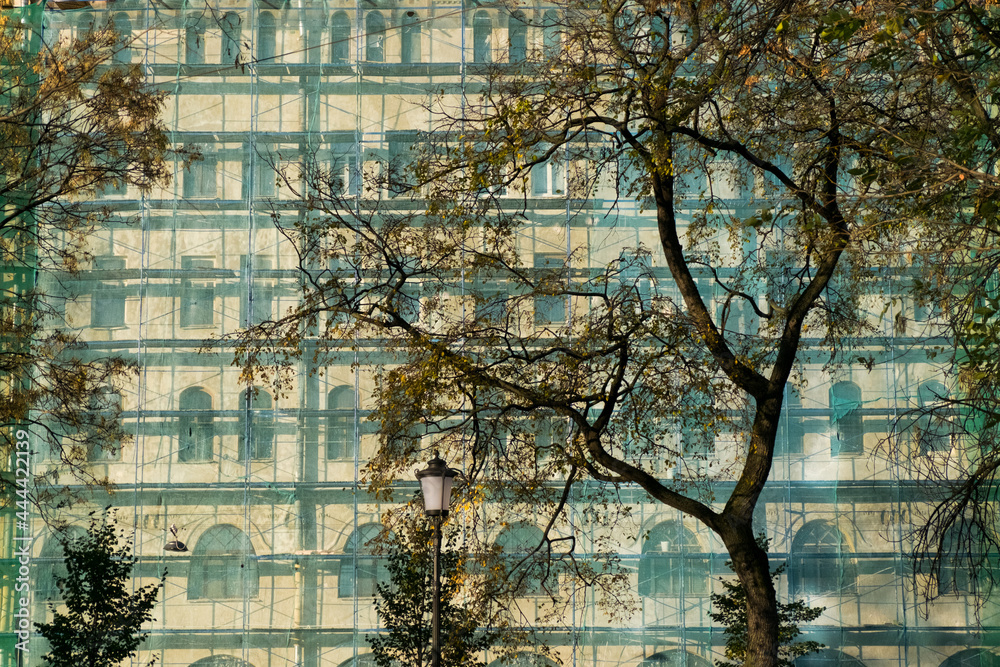 The facade of an old building under reconstruction, covered with a ...